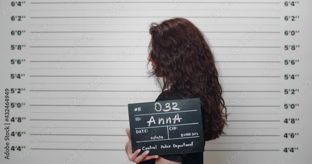 Video „Mugshot of woman with curly hair holding sign for photo in ...