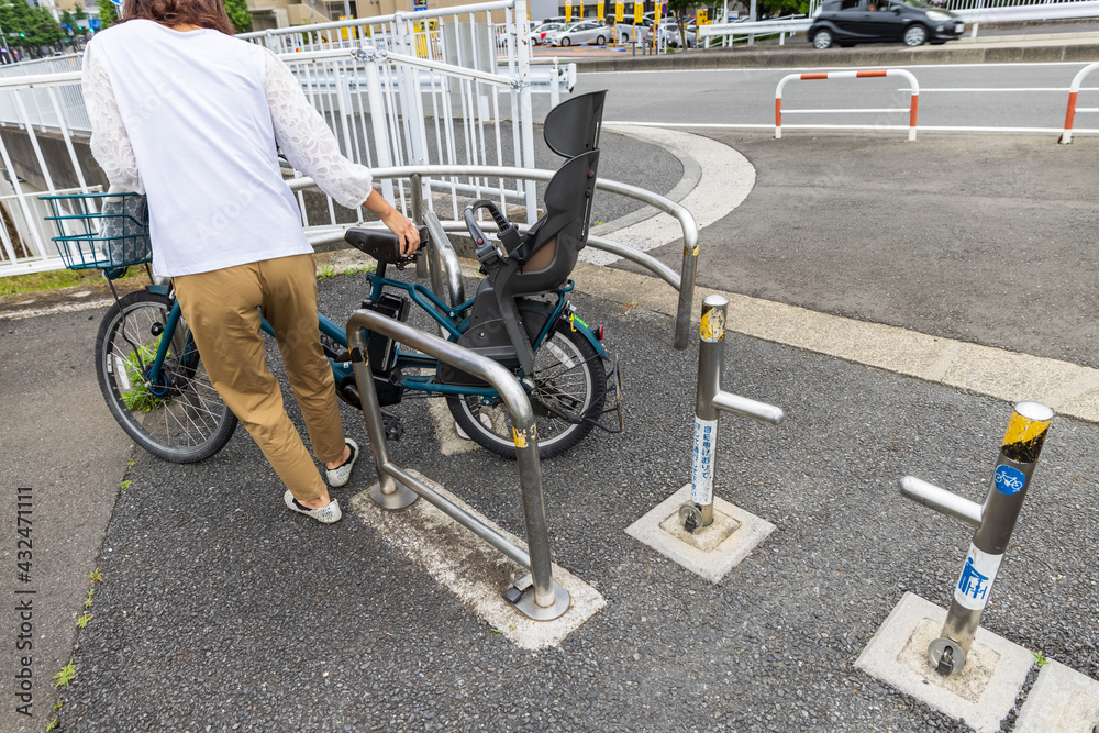自転車専用路に設置された自動車・バイク進入防止のための柵を自転車を押して通り抜ける女性 Stock Foto Adobe Stock