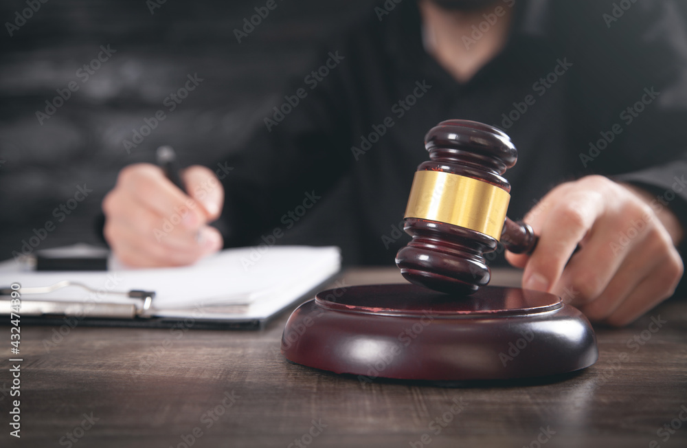 Male judge in a courtroom striking the gavel. Stock Photo | Adobe Stock