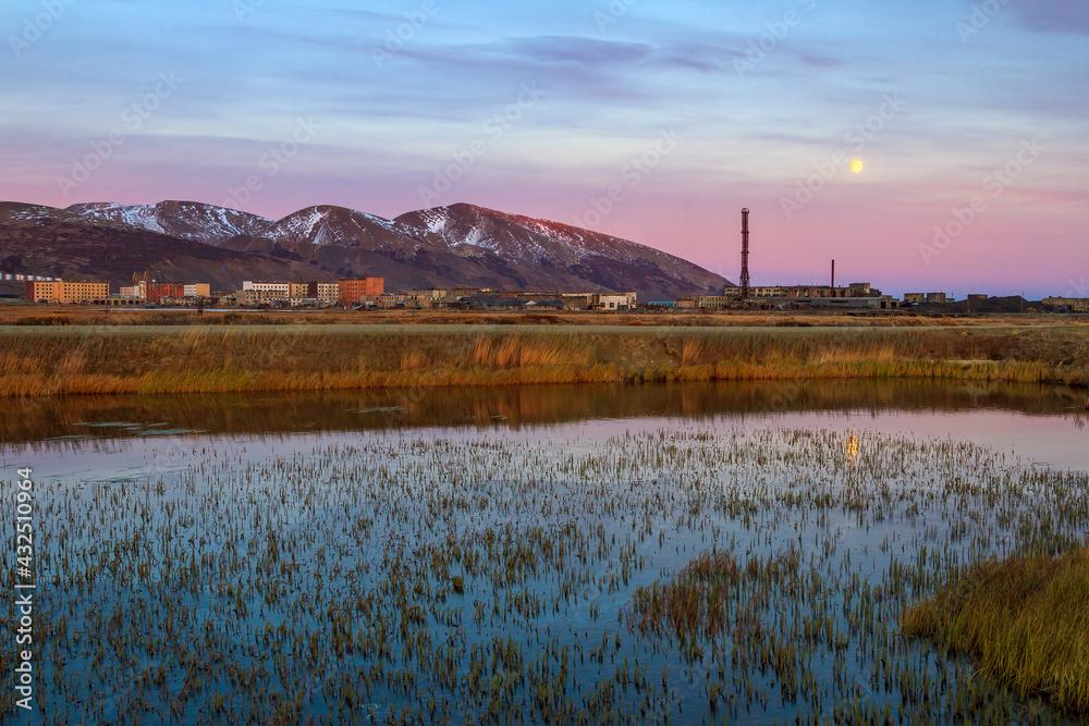 Evening arctic landscape. In the distance, an abandoned port town. View ...
