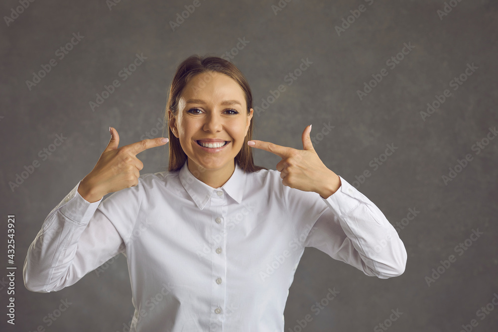Confident smiling young woman pointing with index finger on both hands ...