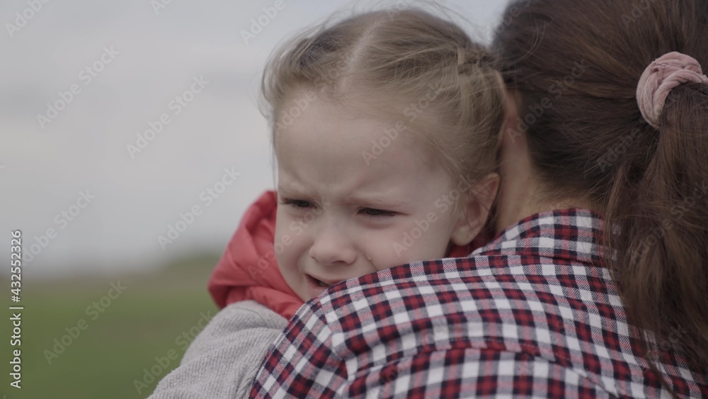 Mommy soothes baby. child is crying in park in arms of mom. family ...