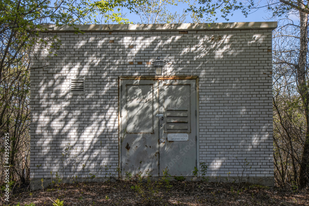 White brick one story windowless building with rusted green metal doors ...