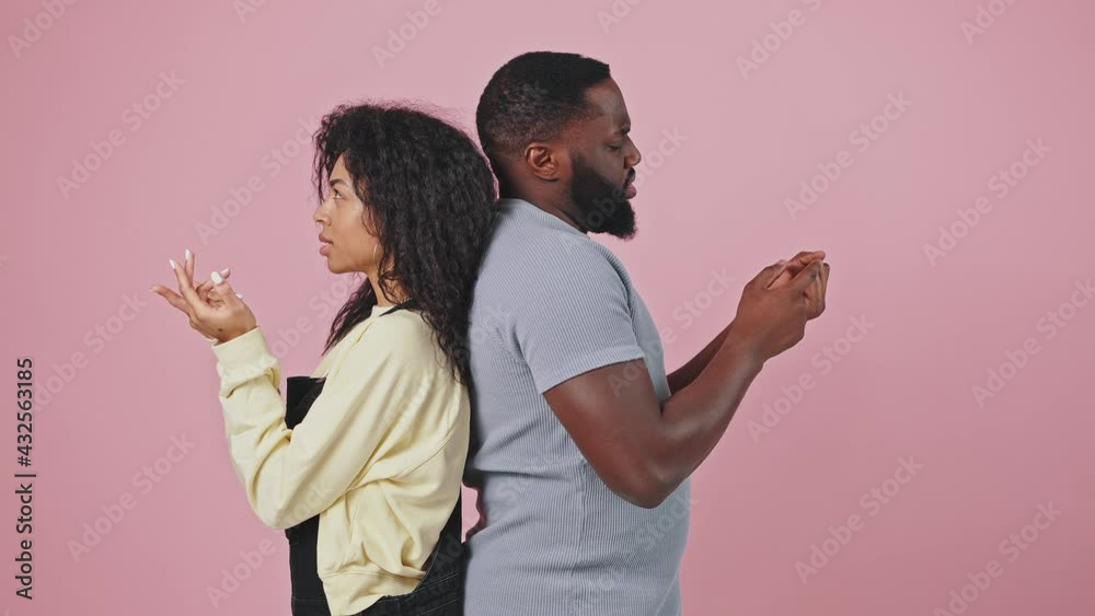 Unsure african american man and woman standing back to back, comparing ...