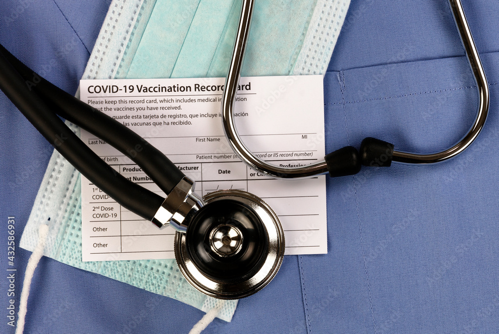 Covid 19 vaccination record card, personal facemask and stethoscope on ...