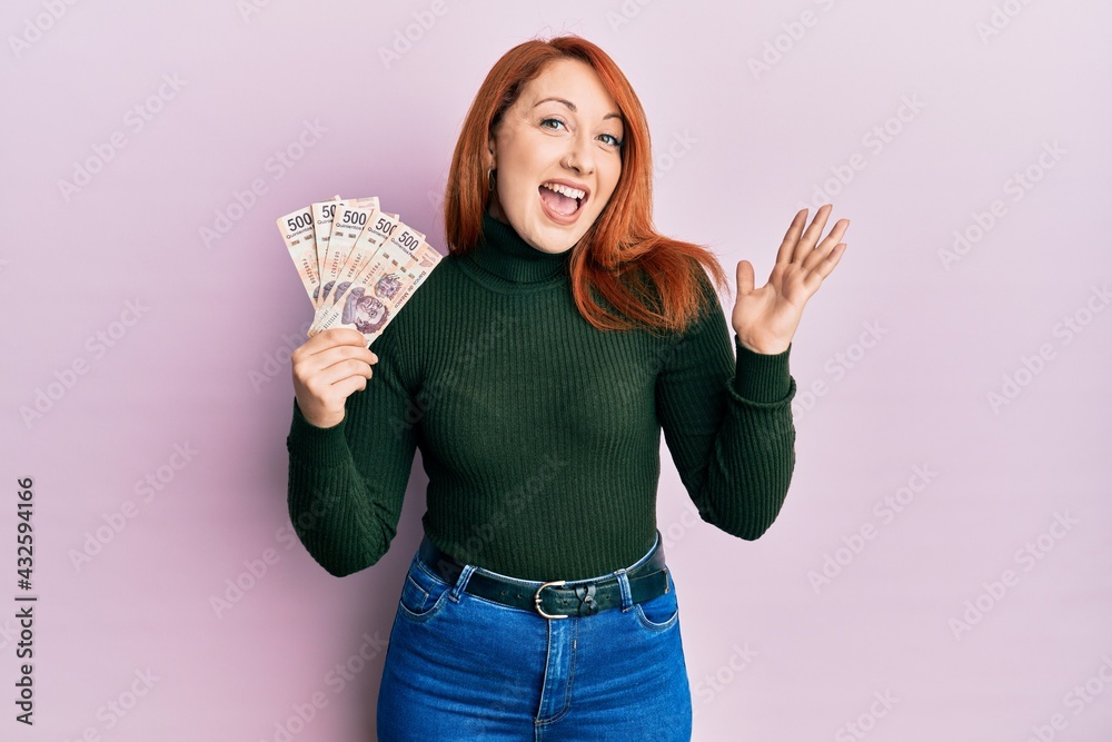 Beautiful redhead woman holding 500 mexican pesos banknotes celebrating ...
