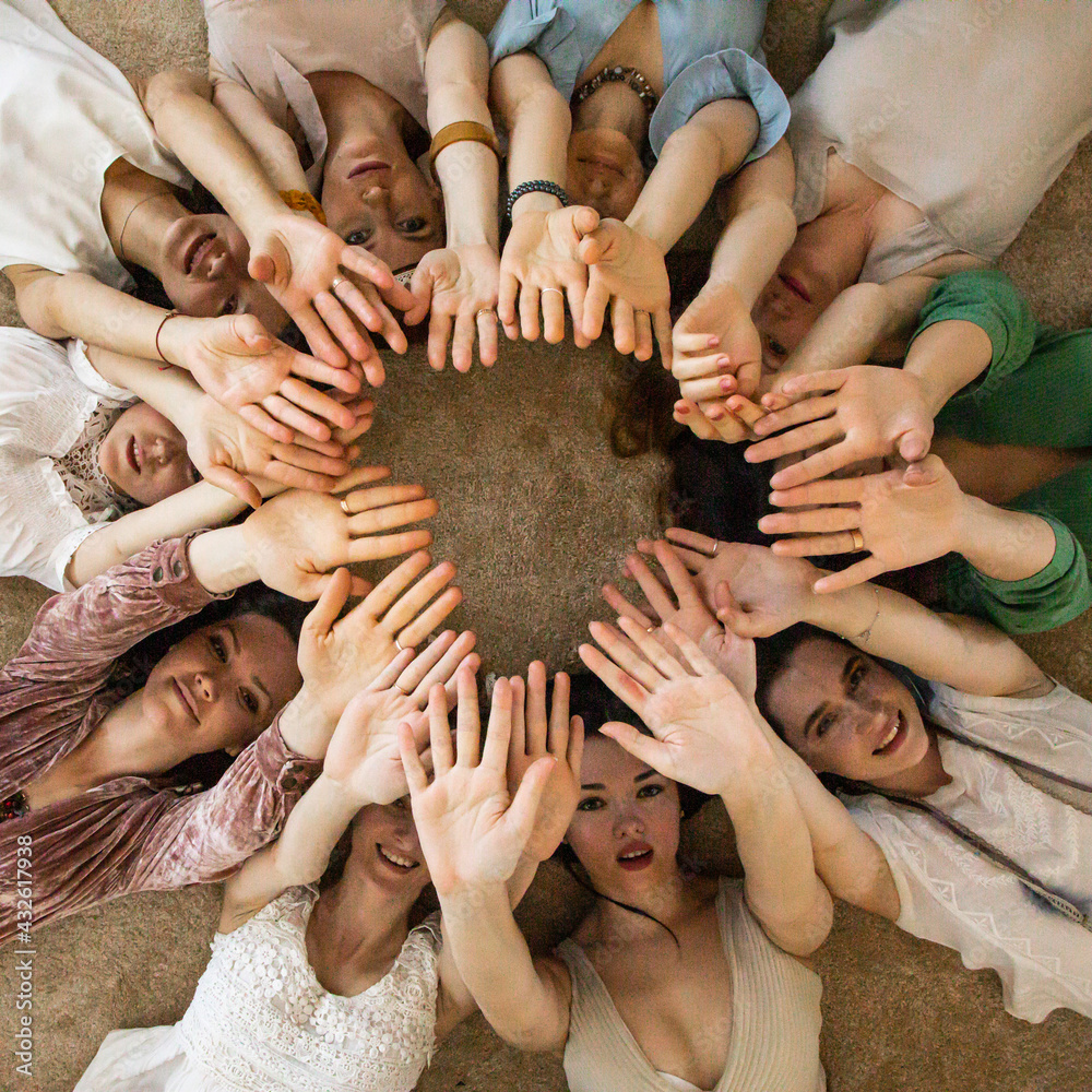 Happy female friends lying circle raising hands together enjoying ...