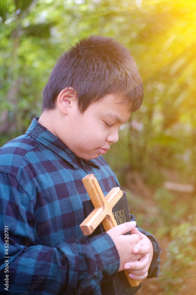 Christian boy prayer to God. The Bible and the cross are in hand. Stock ...