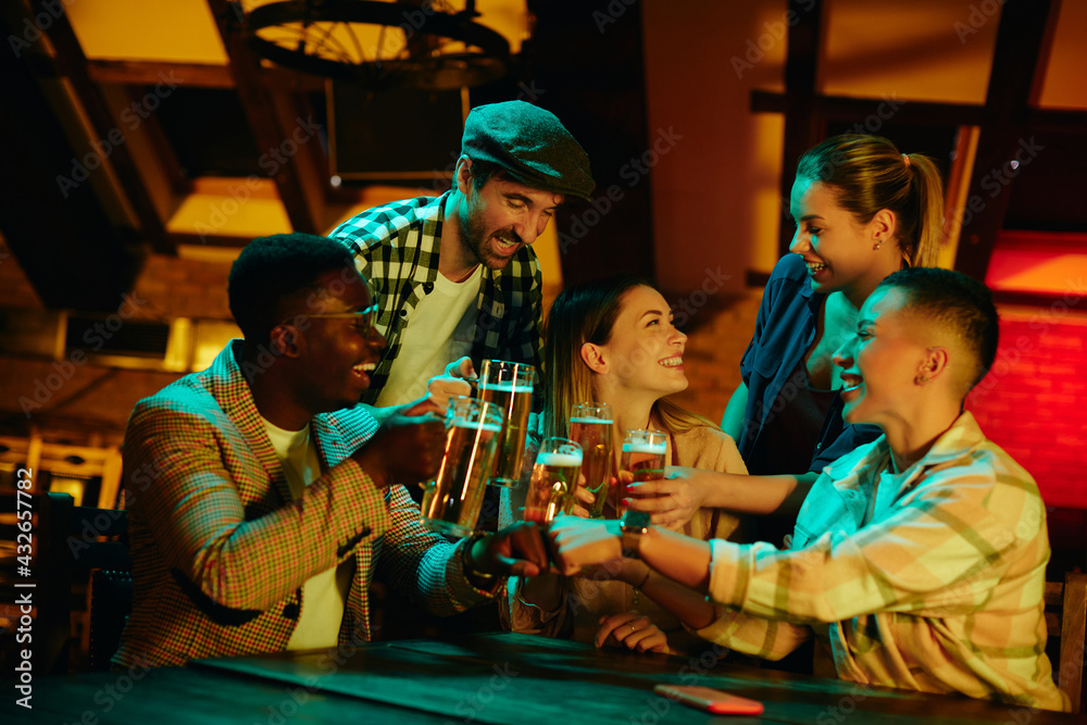 Young happy adults having fun while drinking beer and toasting in a bar ...