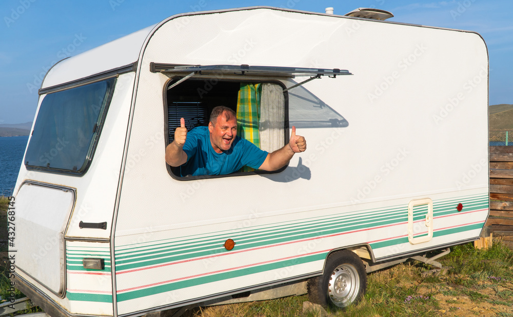 man is relaxing with a travel trailer. caravan, equipped with all ...