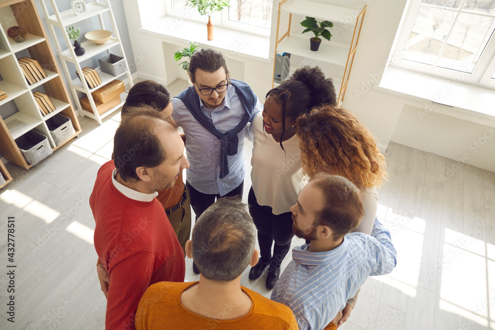 High angle group shot of mixed race people huddling in office. View ...