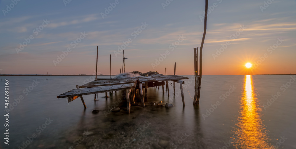 Vue d'un ponton de pêche avec un coucher de soleil sur un étang de la ...