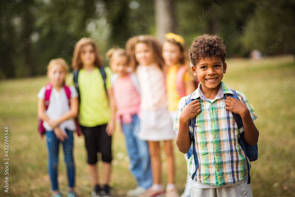 Large group of school kids in nature. Portrait of school boy. Focus is ...
