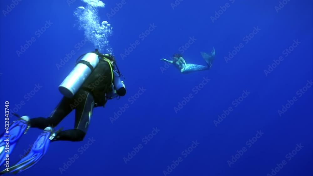 Young woman mermaid poses for camera of cameraman underwater in sea ...