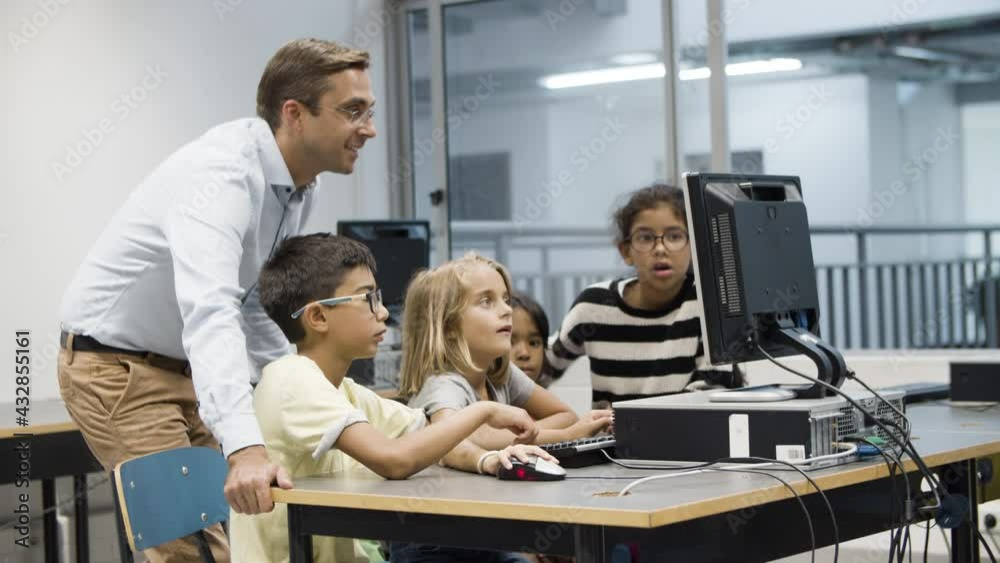 Multietnic children doing task during computer science lesson. Teacher ...