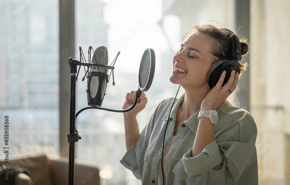 Young beautiful woman recording a song singing into a microphone on ...