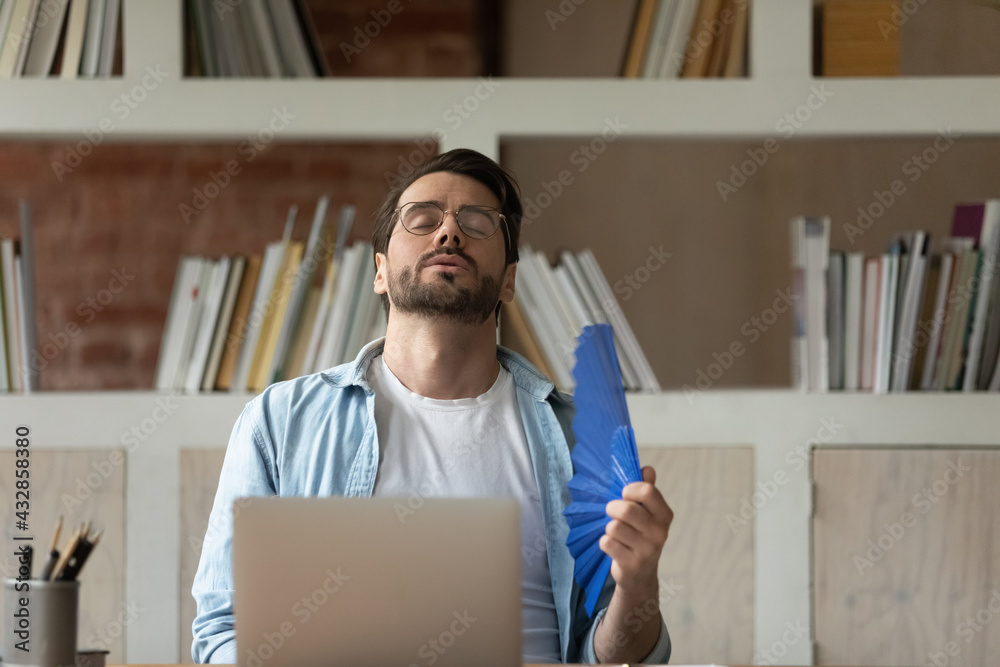 Exhausted overheated businessman in glasses waving paper fan, sitting ...