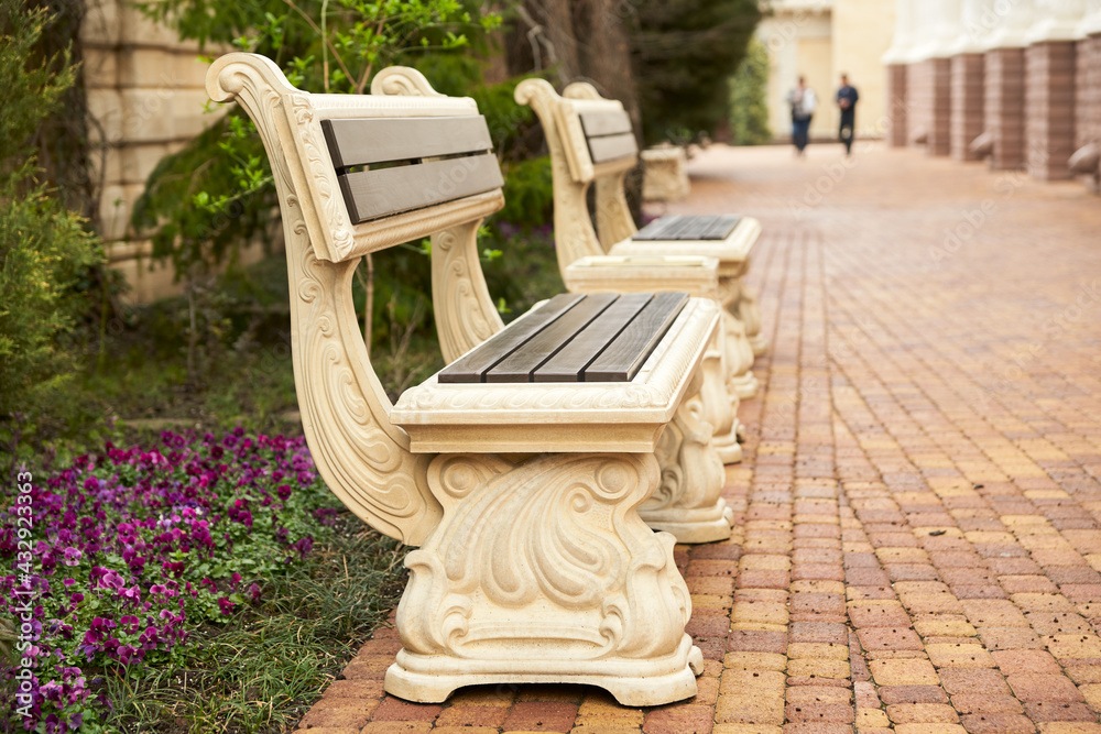Two vintage benches on an alley in the park. At the end of the alley ...