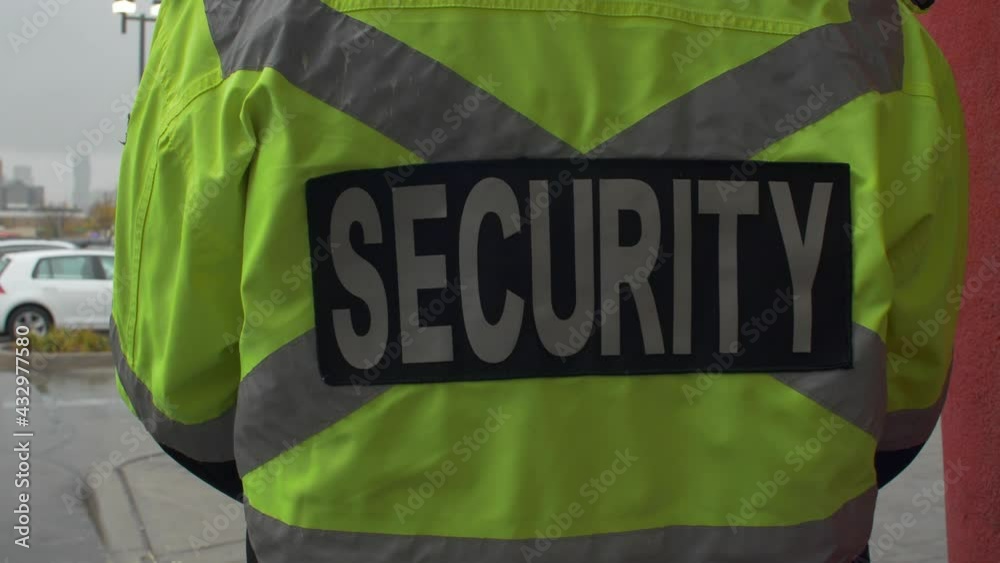 Rear view of a security guard in uniform patrolling in a commercial ...