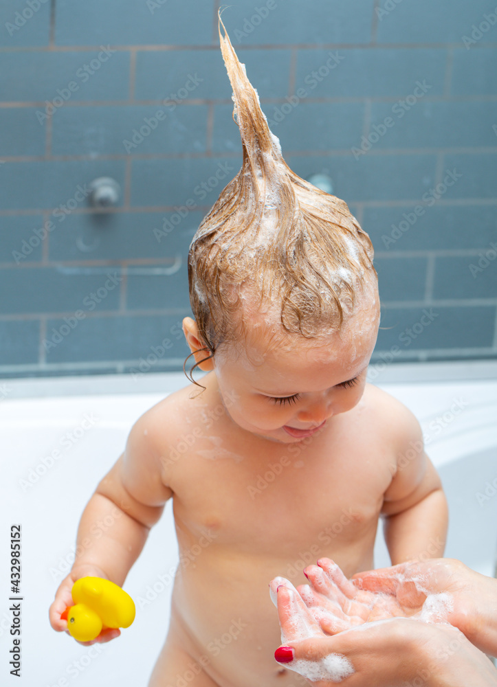 Smiling beautiful baby bathing in shower. Little baby child is washing ...