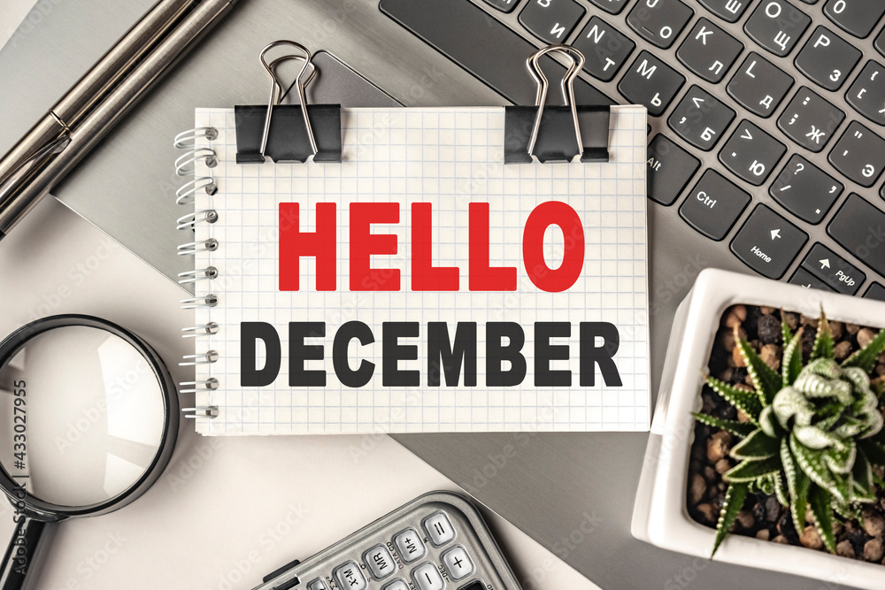 HELLO DECEMBER text on a notepad and laptop, office tools. Business ...