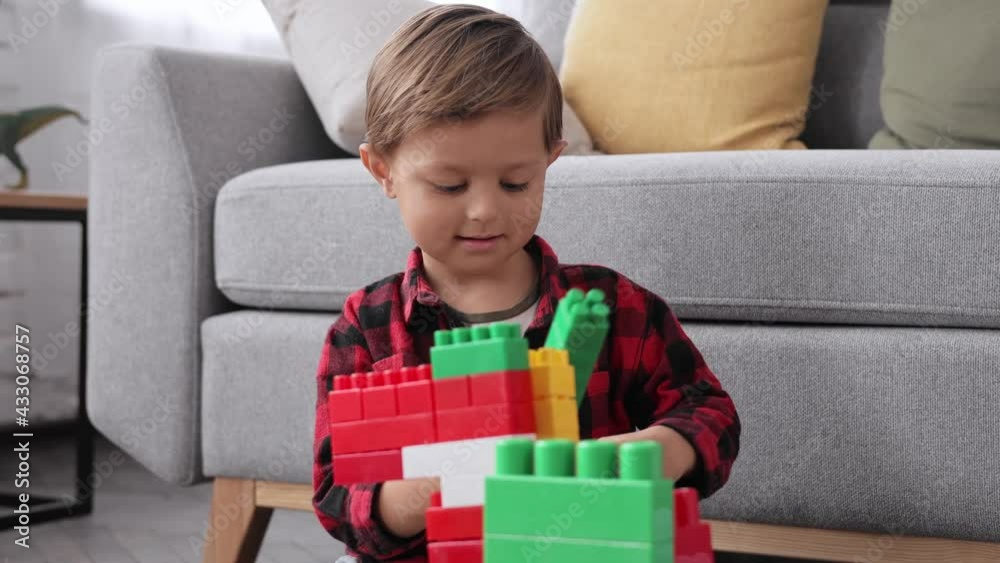 A little boy builds a tower using colorful constructor blocks sitting ...