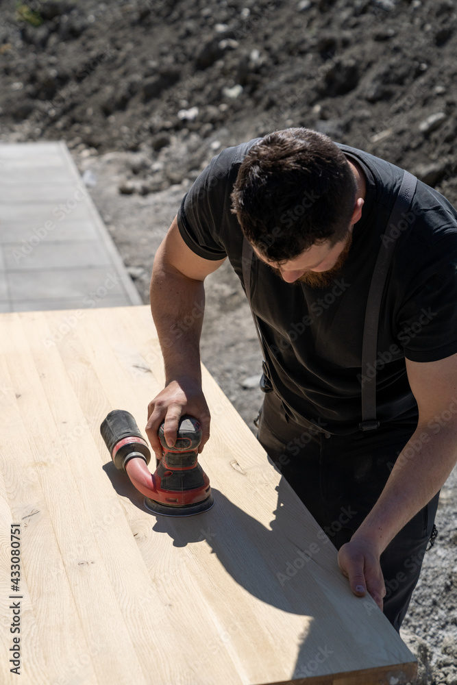 construction worker using a cordless power sander to sand a massive ...