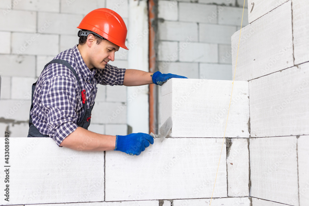 Master foreman puts a wall of aerated concrete blocks when building a ...