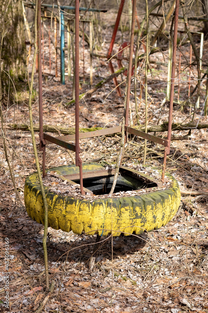Old broken swing made of metal and car tire on abandoned playground ...