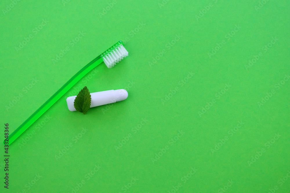 Toothbrush and a small tube of toothpaste with a mint leaf on a green ...