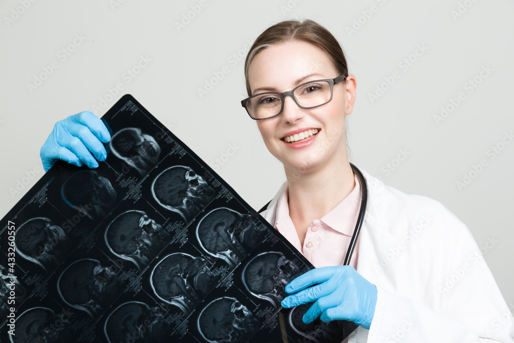 smiling female doctor is handling an x-ray image scan of a human head ...