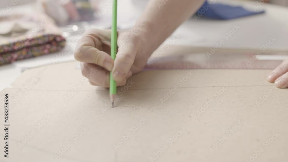 Seamstress writing notes on sewing pattern, making clothes in fashion ...