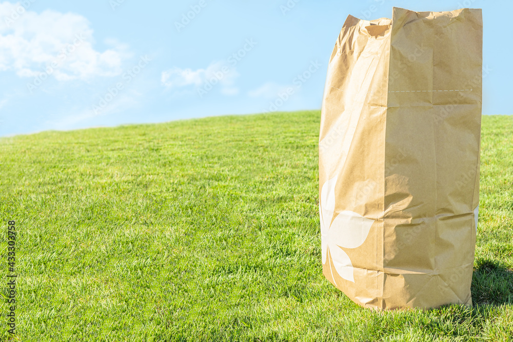Brown craft paper bag for yard waste place on green grass field against ...