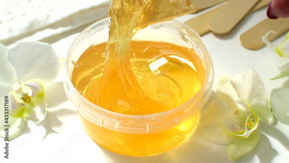 Sugar paste in a transparent jar on a white background. A master stir the sugar paste before ...