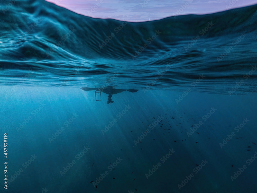 Underwater view of a boat bottom part and fishes swimming in clear blue ...