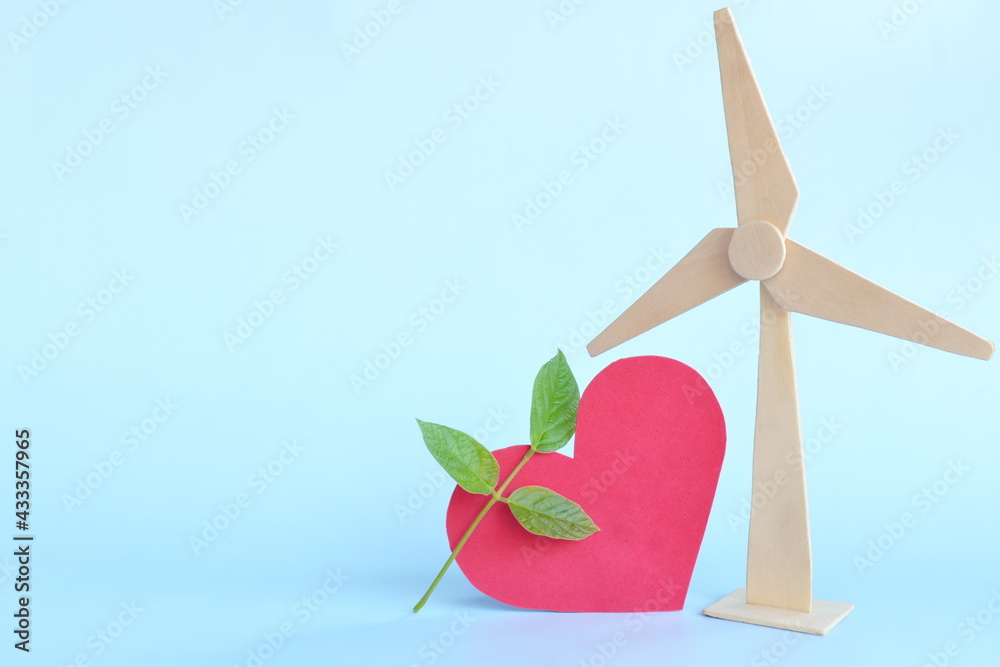 Wooden wind turbine model with fresh green leaves and red heart shape ...