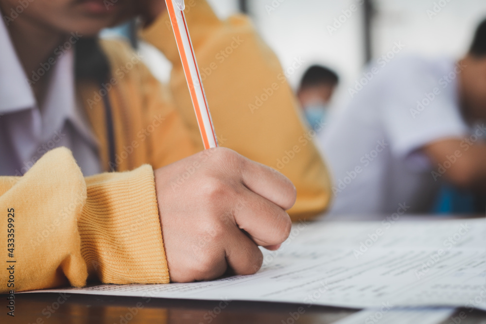 Students writing and reading exam answer sheets exercises in classroom ...