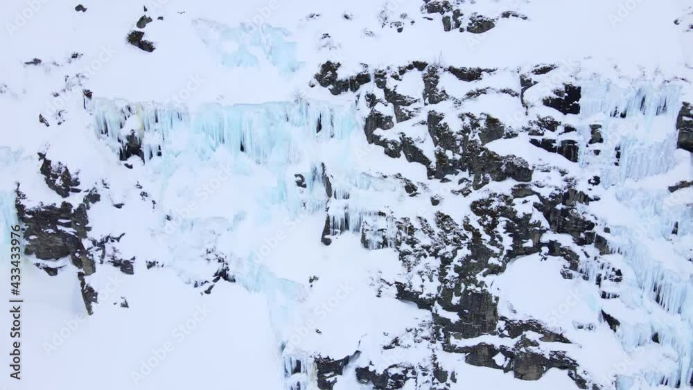 Massive long frozen icicles hanging of the side of a cliff on a ...
