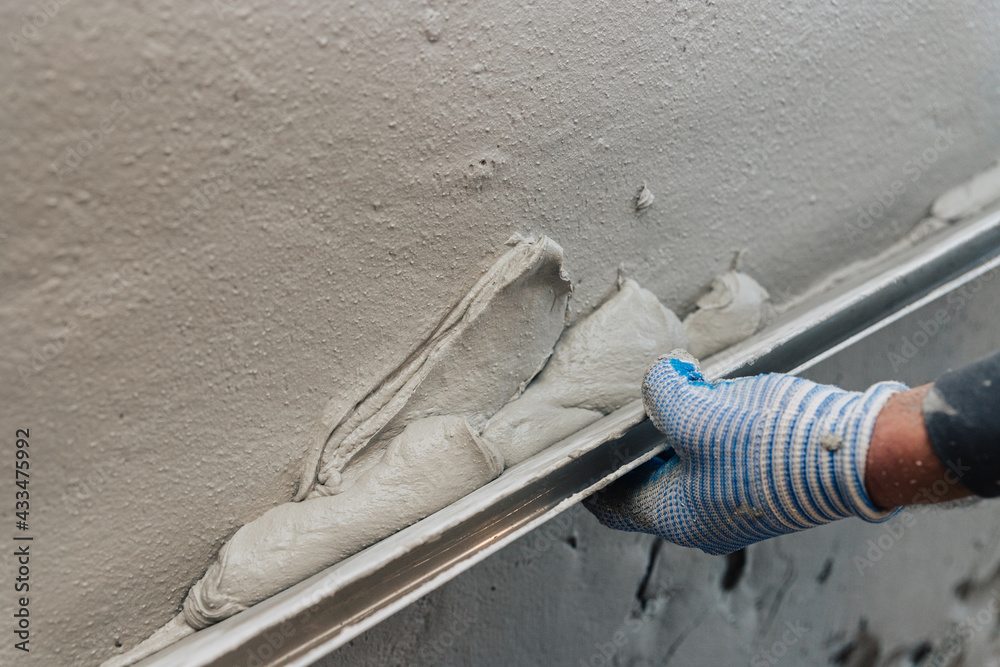 The final stage of plastering the walls. A worker levels the plaster ...