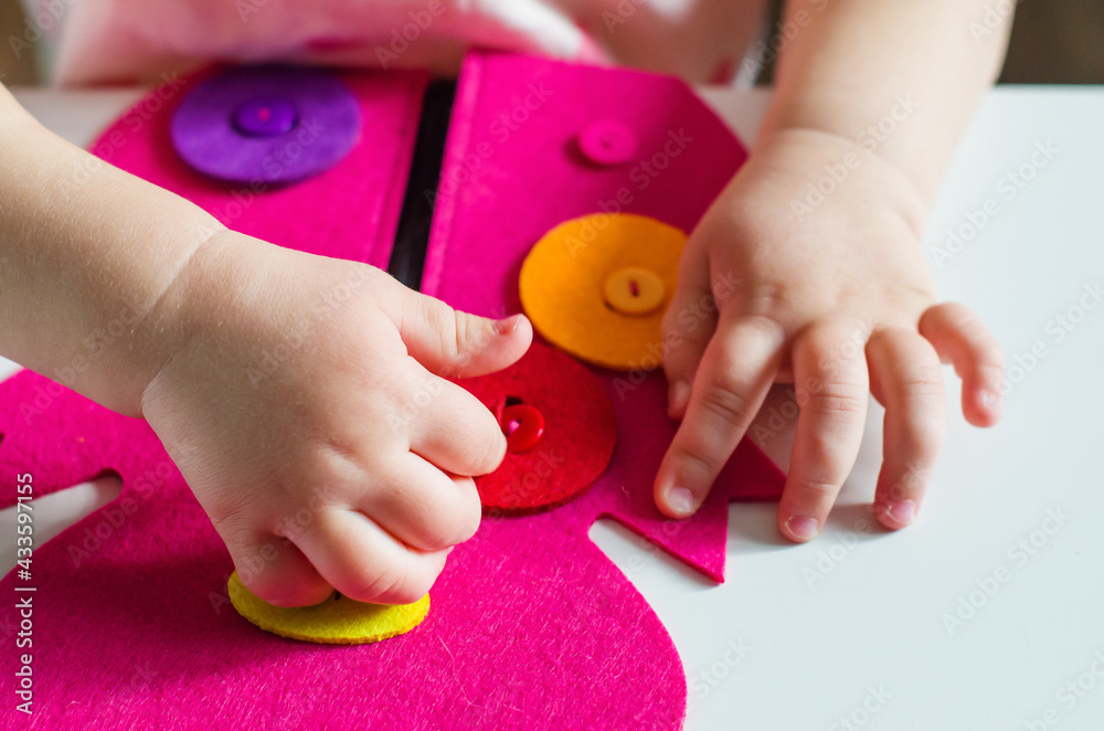 Little child hands buttoning a Montessori toy. Practical life skills ...