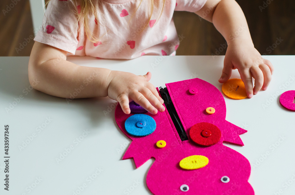 Foto de Little child hands buttoning a Montessori toy. Practical life ...