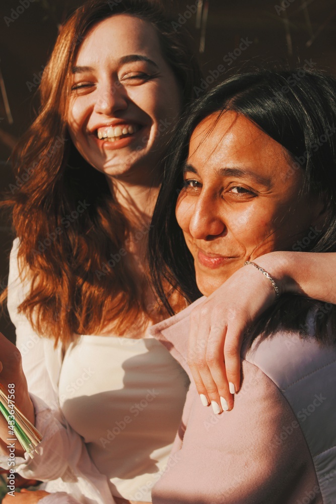 two young women of different skin color, ethnicity and culture hugging ...