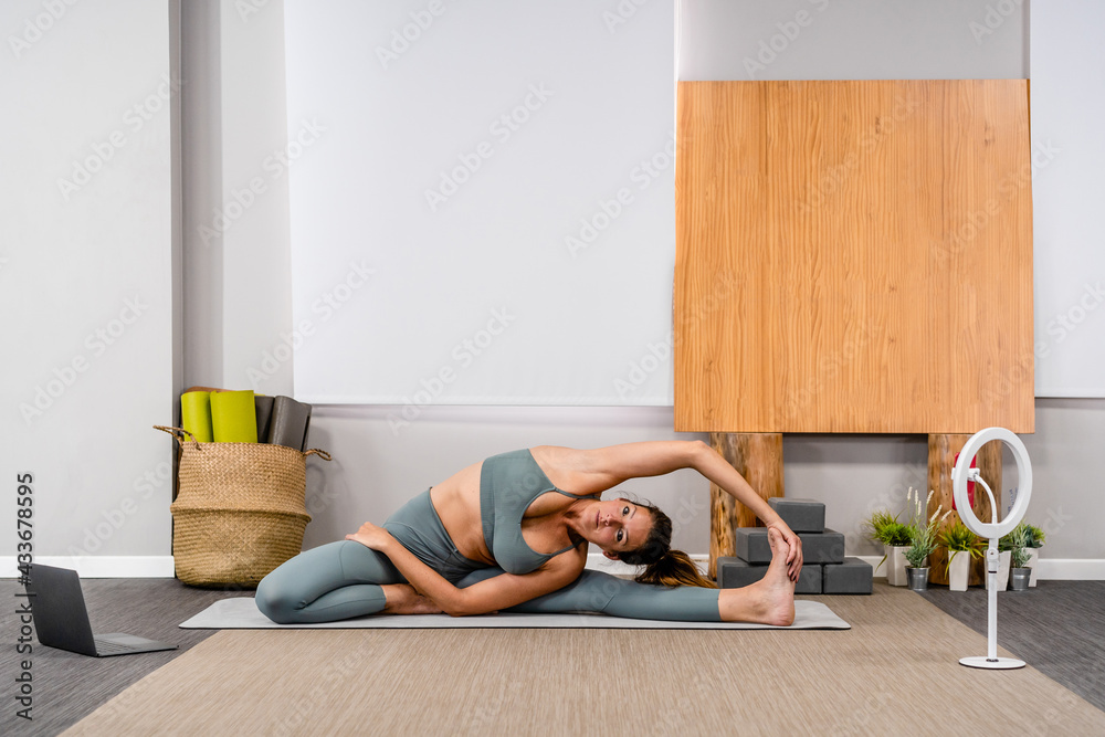 Full body of flexible calm young lady in sportswear stretching spine in ...