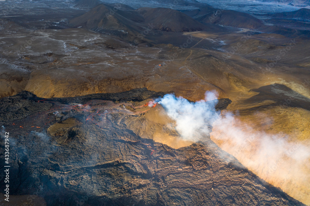 From above columns of smoke and magma sparks out of the volcano hole ...