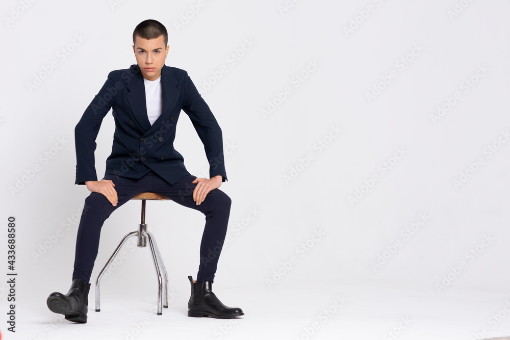 Serious male model in fashionable suit sitting on white background in ...