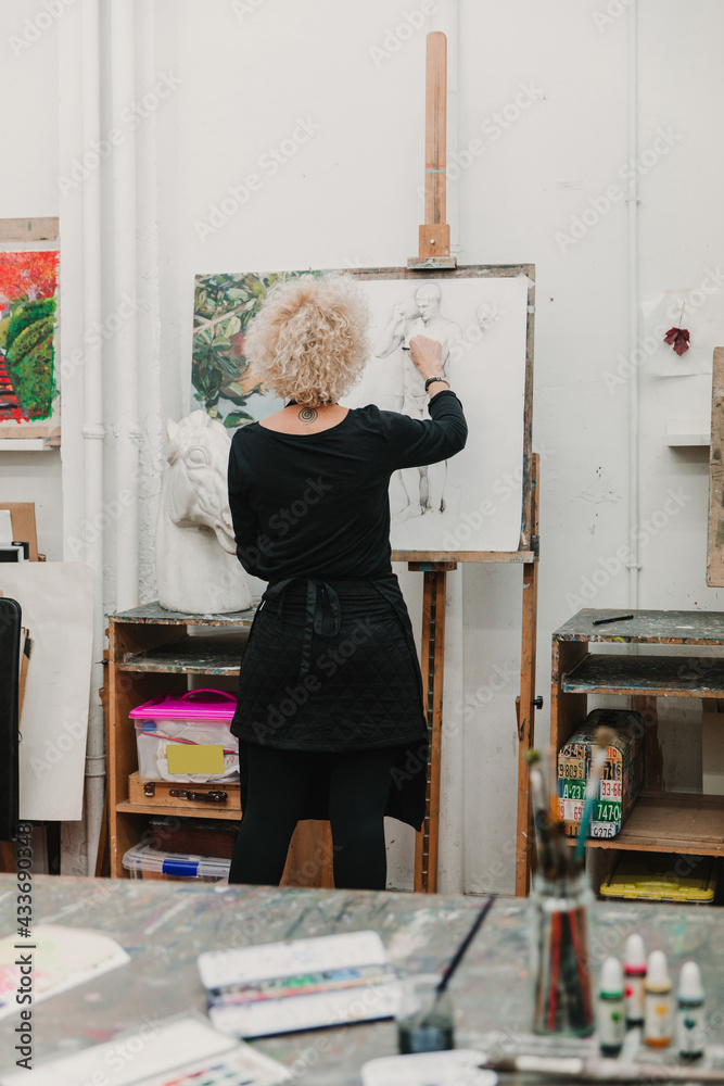 Back view of anonymous female artist creating drawing of human with ...
