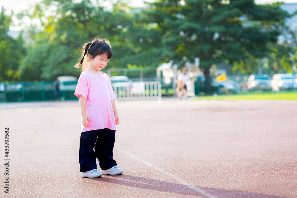 Cute Asian girl is standing making scheming face. Kid thinking and ...