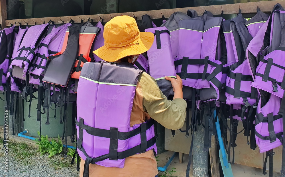 Tourists in yellow hats are choosing the right size purple life jacket ...