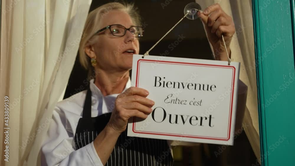 Female shop owner turning ouvert ferme sign in French on cafe glass ...