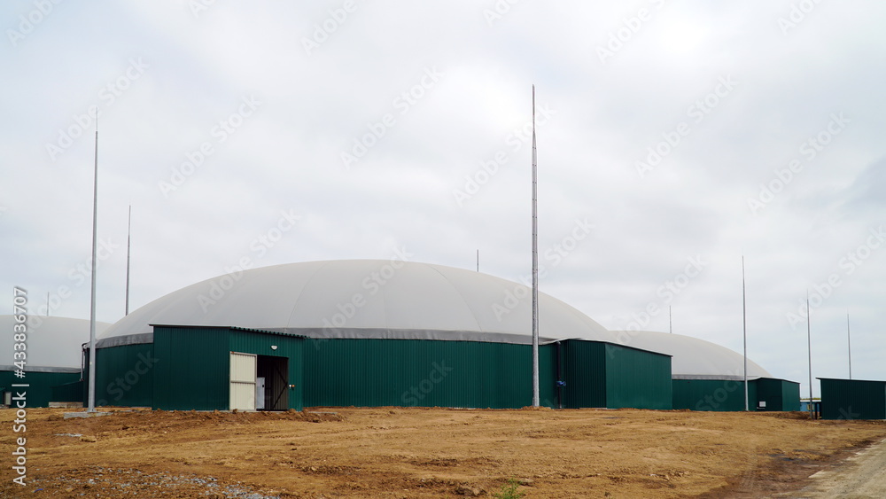 Biogas. Aerial view of a biogas plant and a farm in green fields. Renewable energy from biomass ...